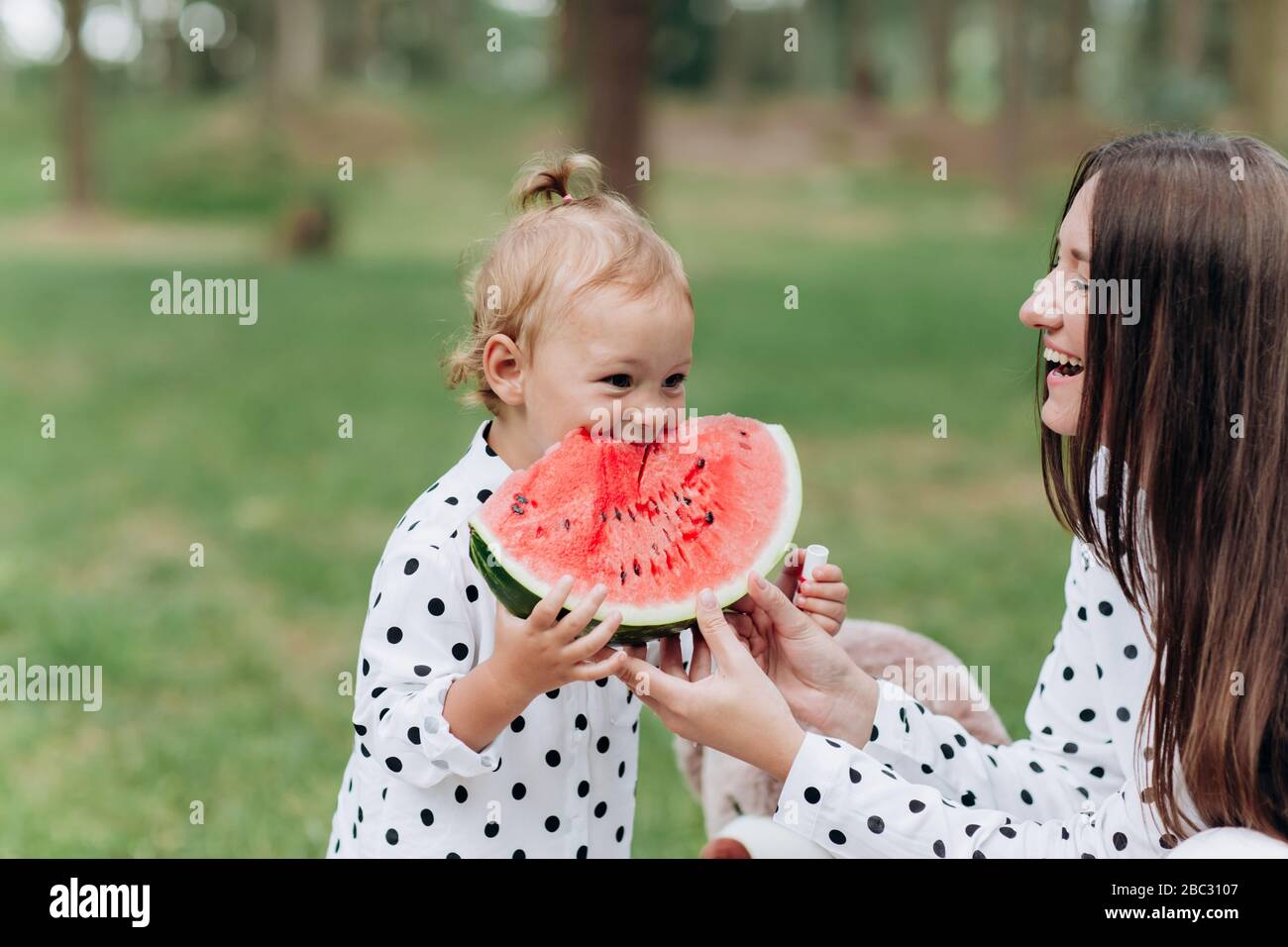 happy mother and daughter eat watermelon in summer park. Happy smiling ...