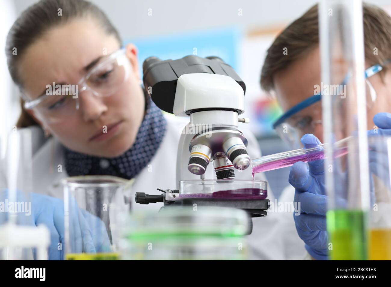 People look at reaction liquid under microscope Stock Photo - Alamy