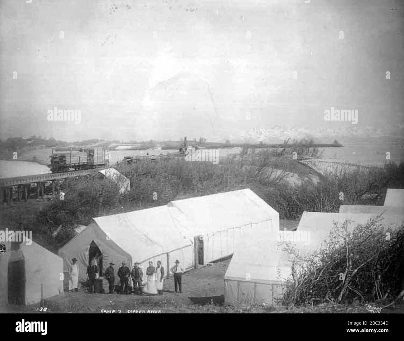 Group of men including mess hall workers posing in front of tents with ...