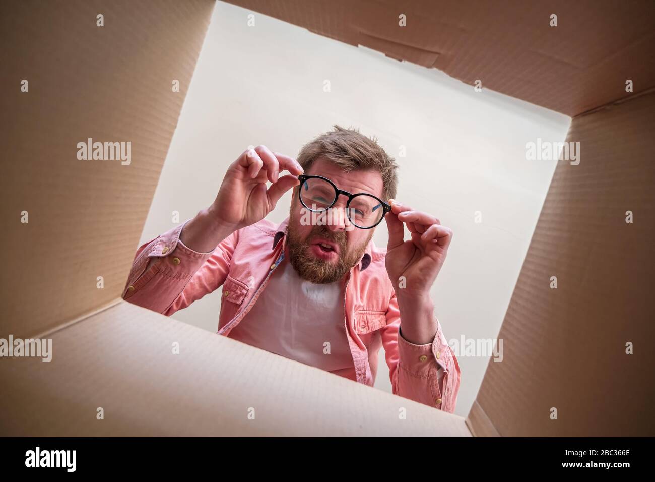 Strange man looks at the bottom of an unpacked delivered box with a ...