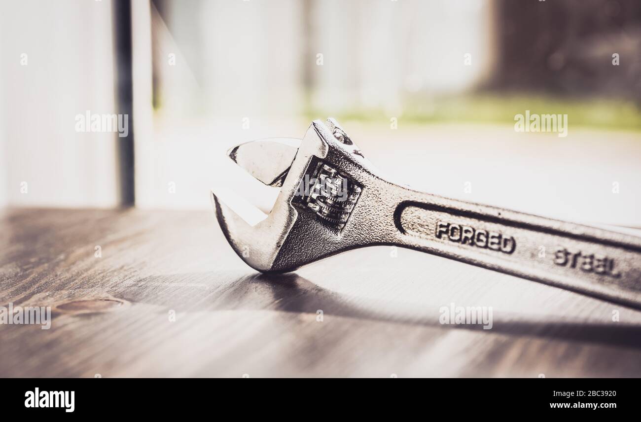 French key, wrench, made with forged steel isolated on wooden worktop ...