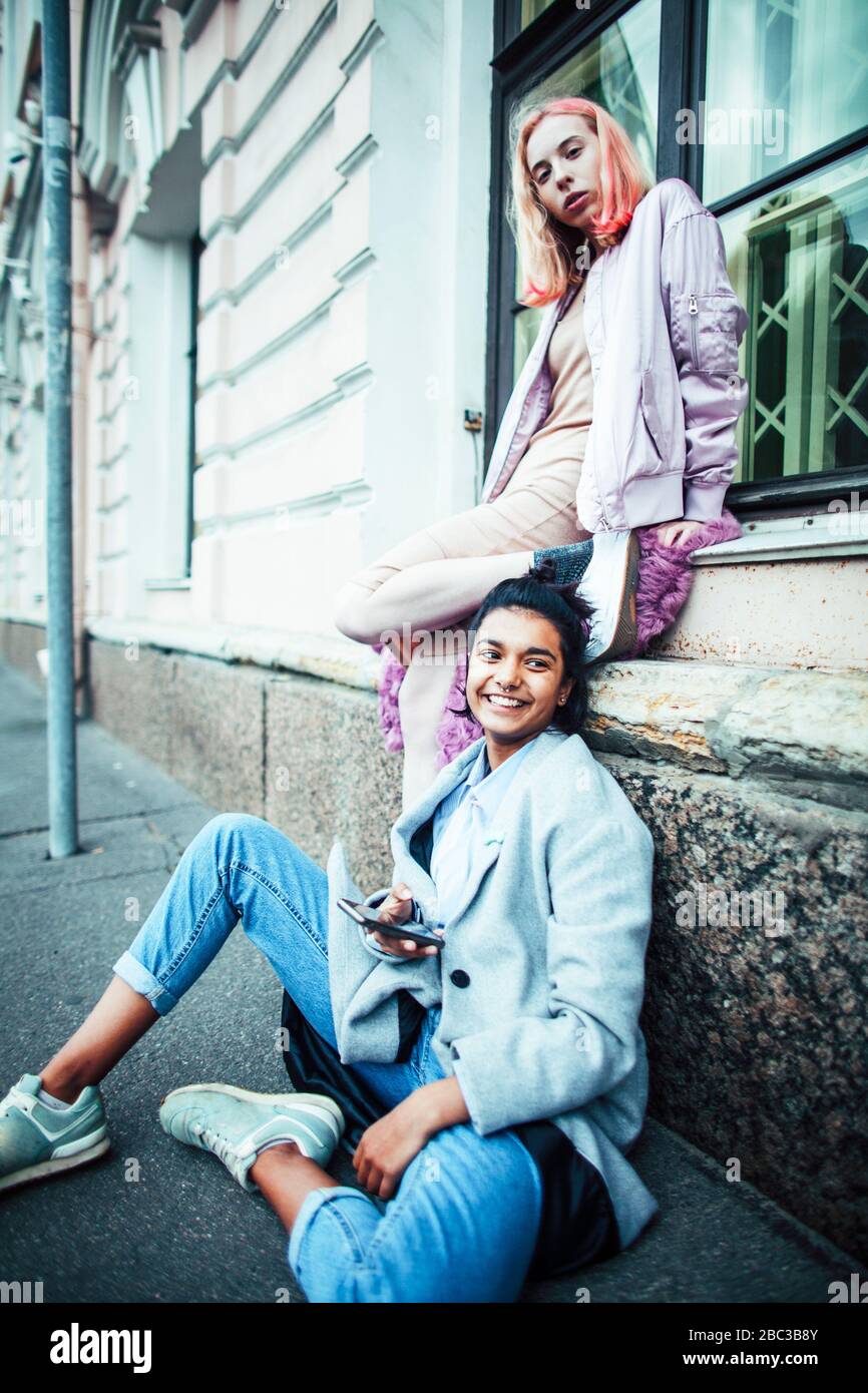 Two teenage girls infront of university building smiling, having fun ...