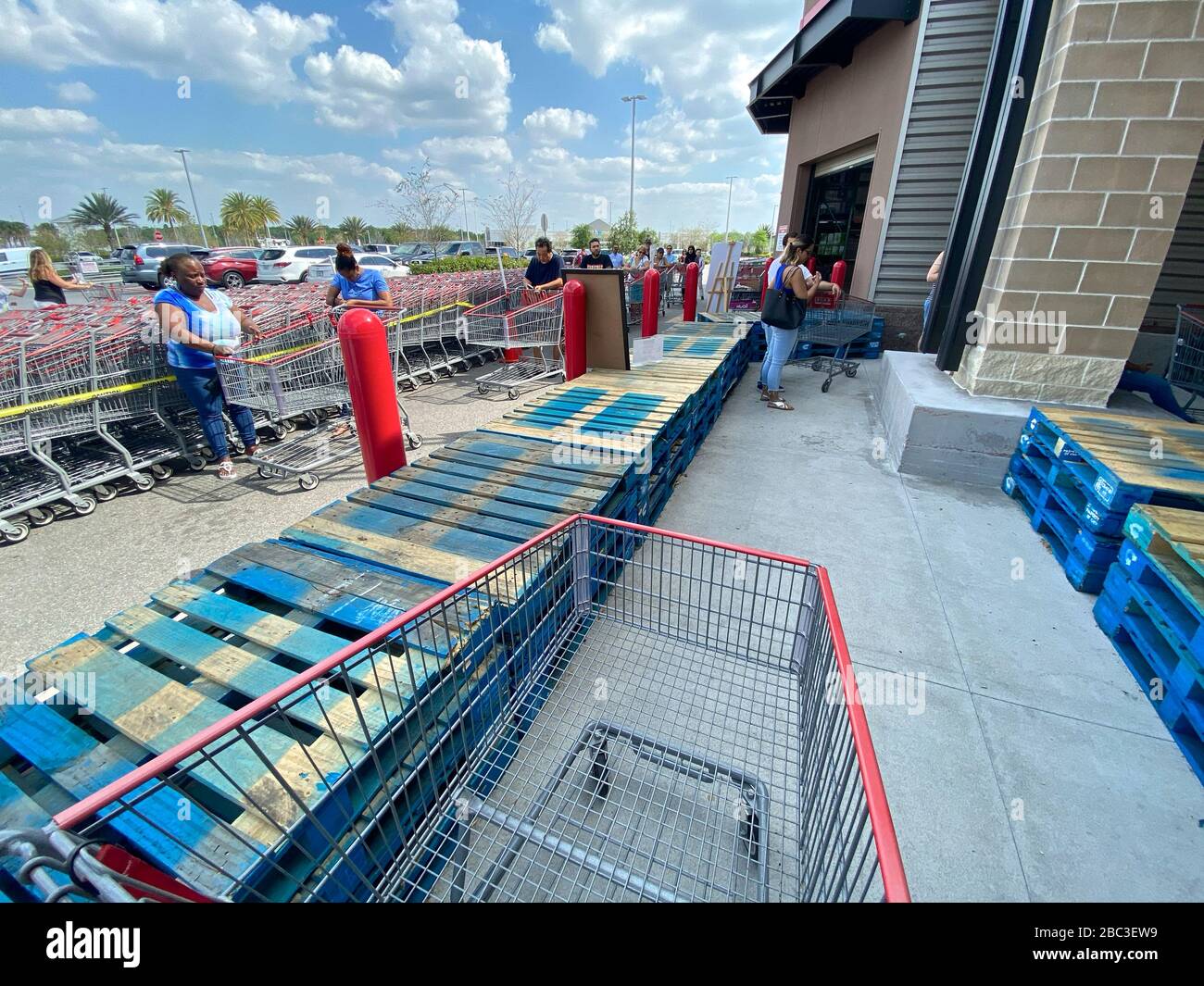 Shoppers line up at Costco maintaining social distancing. Wooden ...