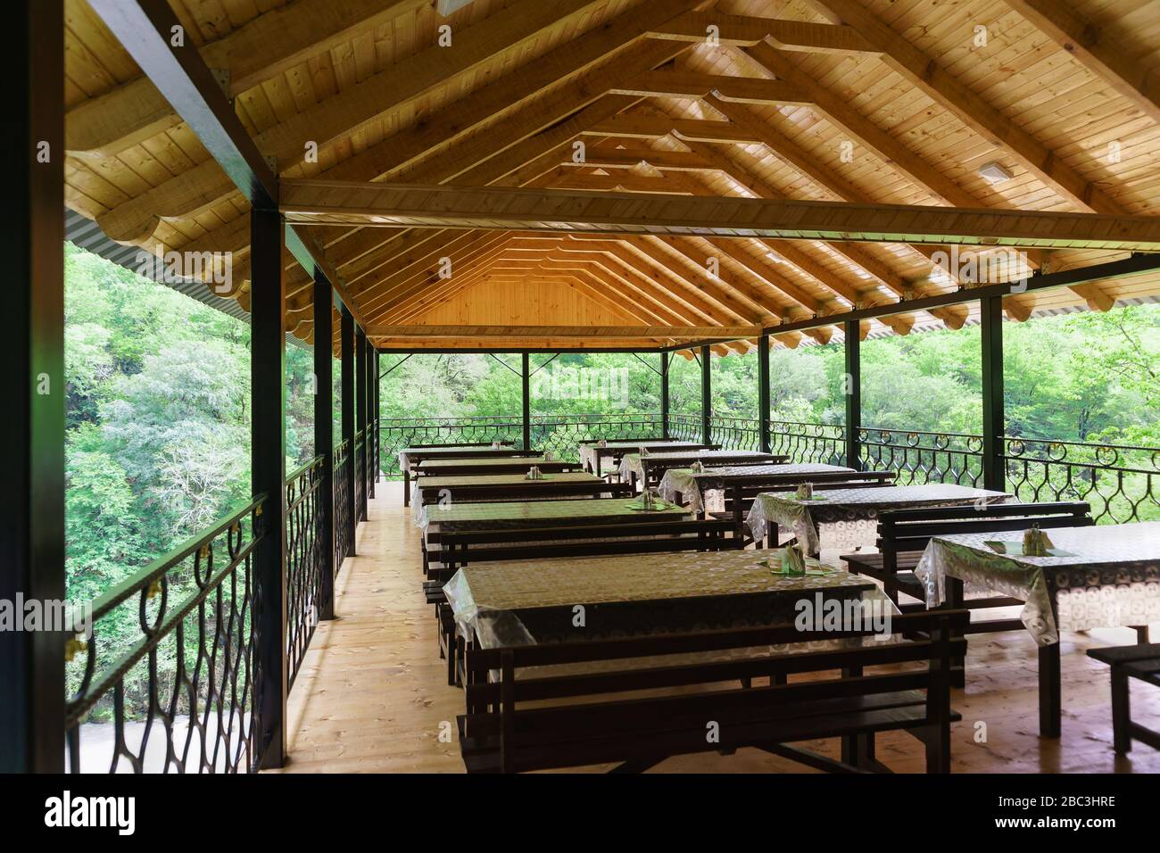 The interior of an open cafe over the river in the mountains. Wooden ...