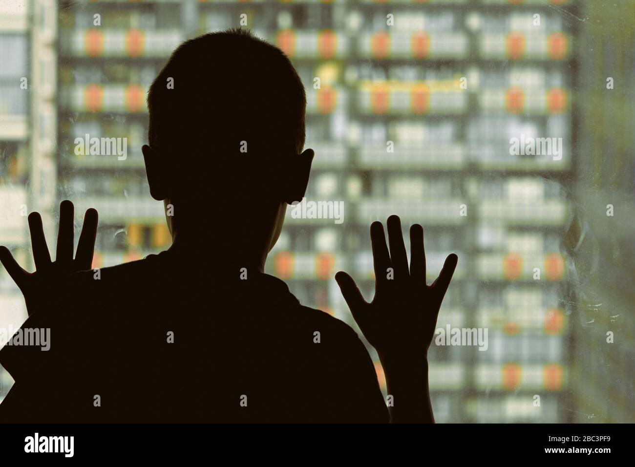 Boy holds hands on window amid apartment buildings Stock Photo - Alamy