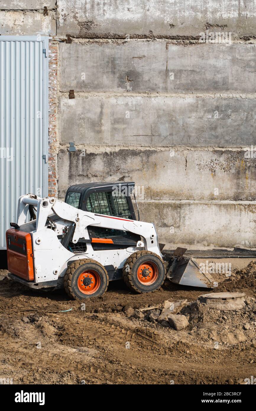 White skid steer loader at a construction site working with a soil ...