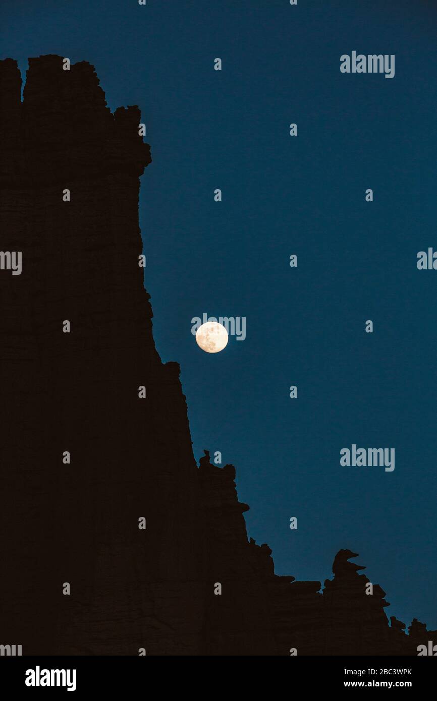 almost full moon rises over bizarre desert landscape at fisher towers ...