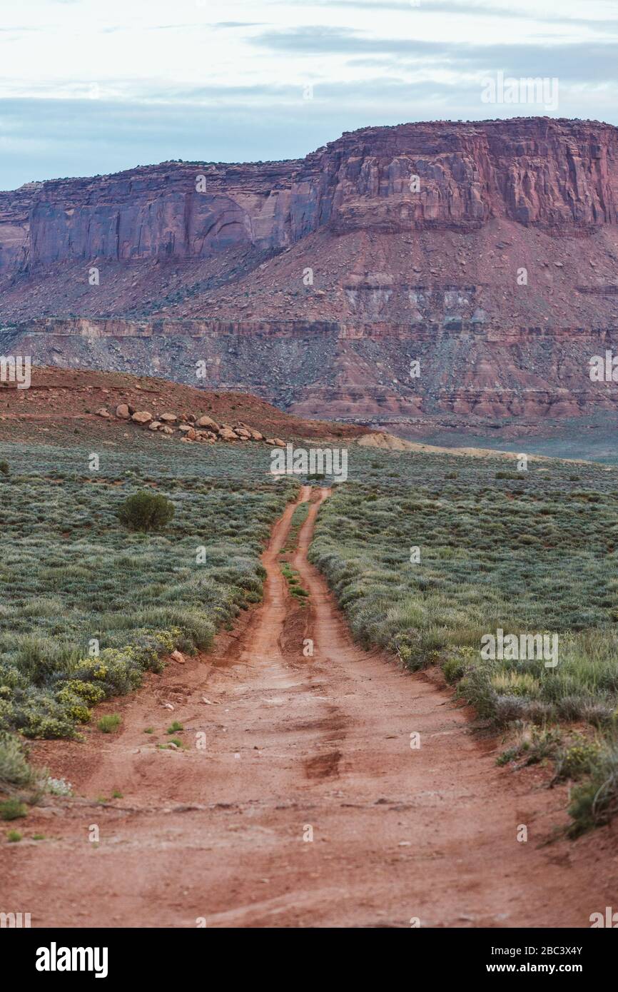double track dirt road in the desert beneath red rock buttes of utah ...