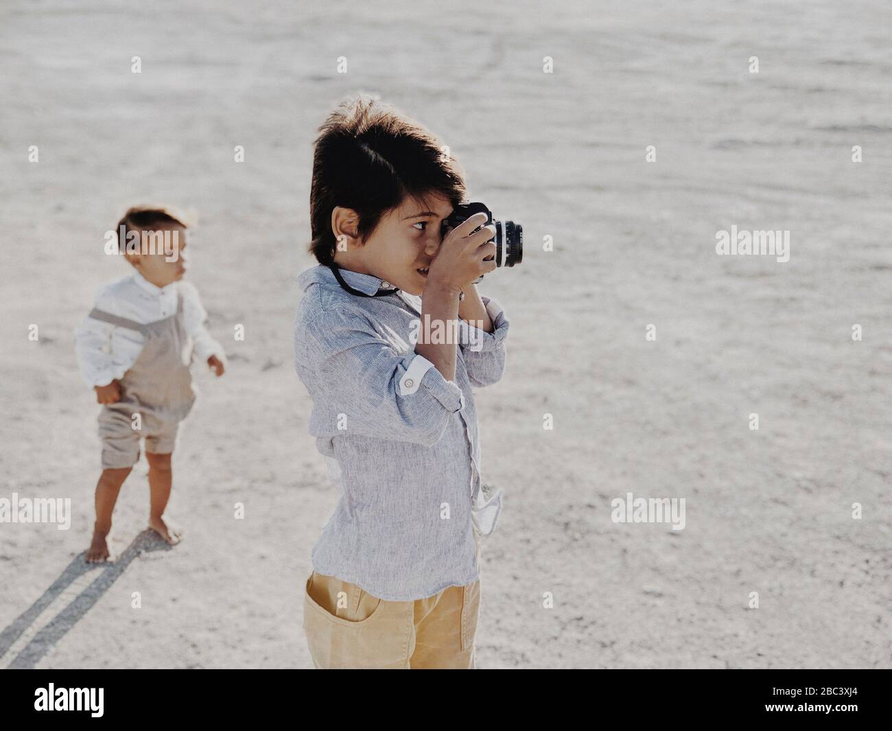 Kid takes photo with vintage camera as other kid stands in background ...