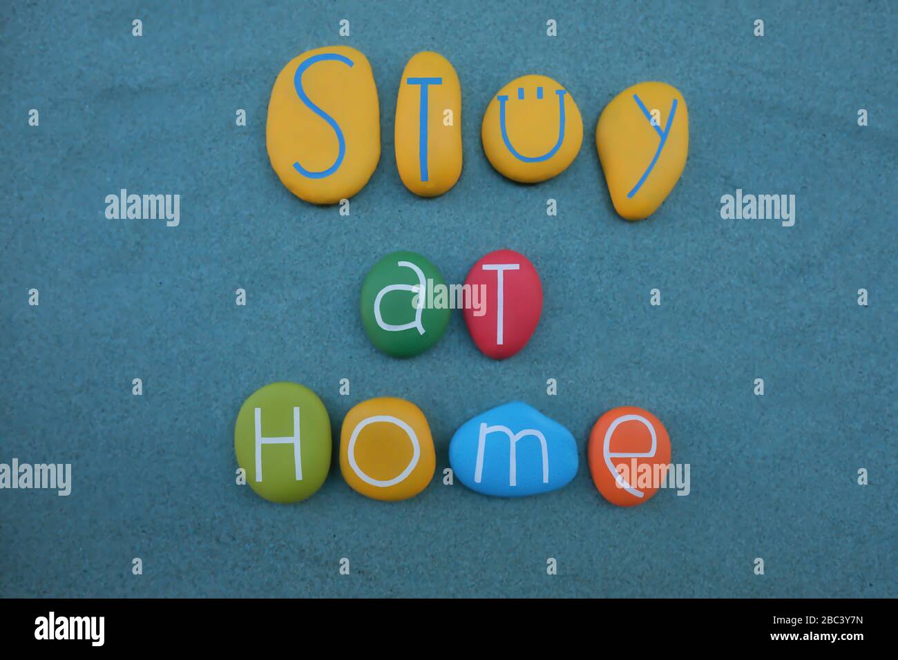 Stay at home text composed with multi colored stone letters over green ...