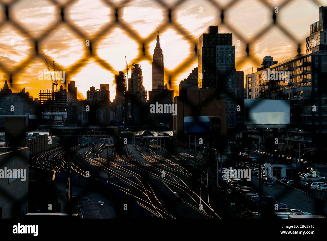Empty train tracks glowing from behind a fence at sunset in New York ...