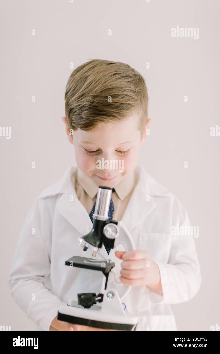 Young child in labcoat looking into a microscope Stock Photo - Alamy