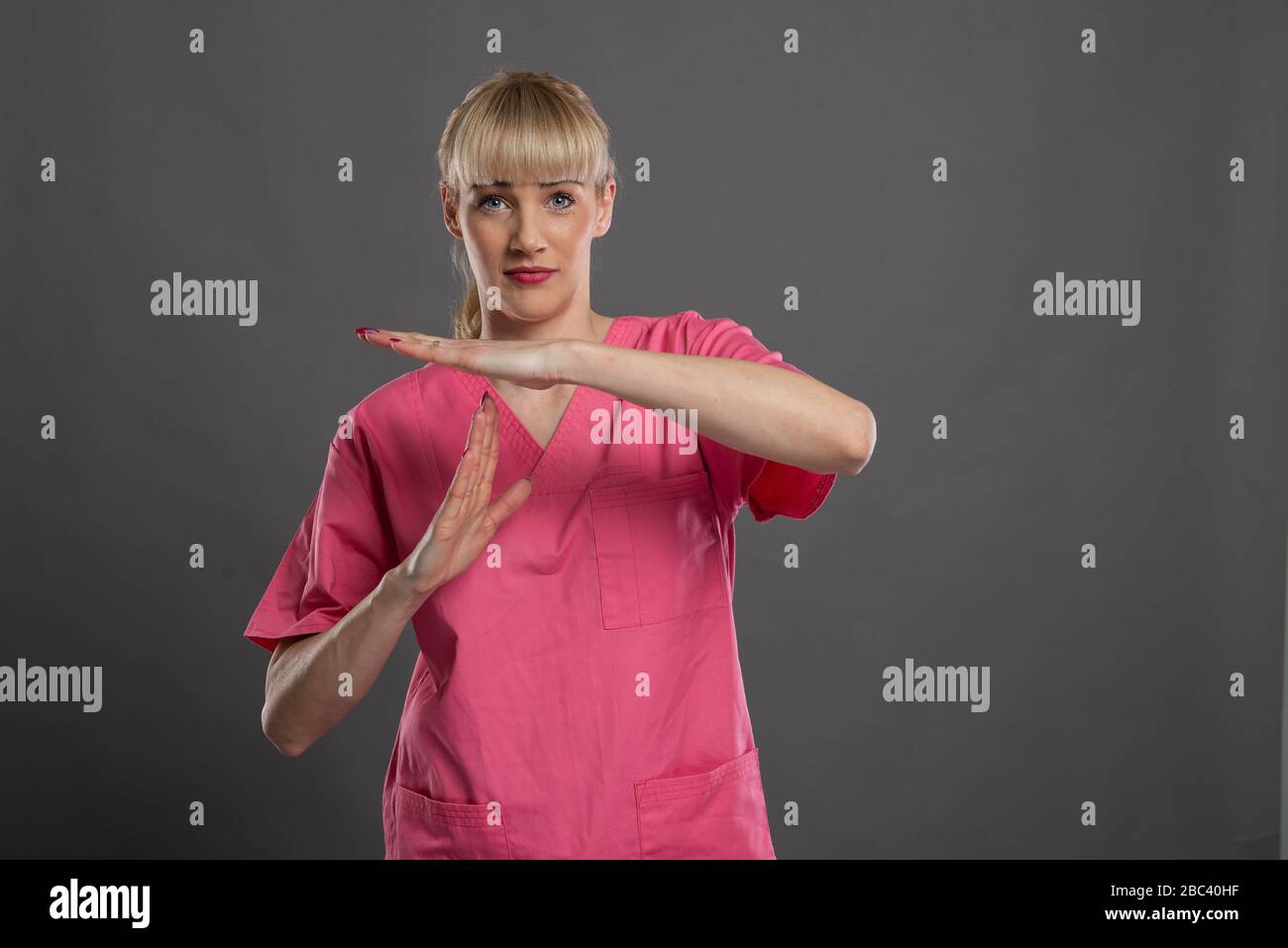 Portrait of young attractive female nurse showing time out gesture on ...