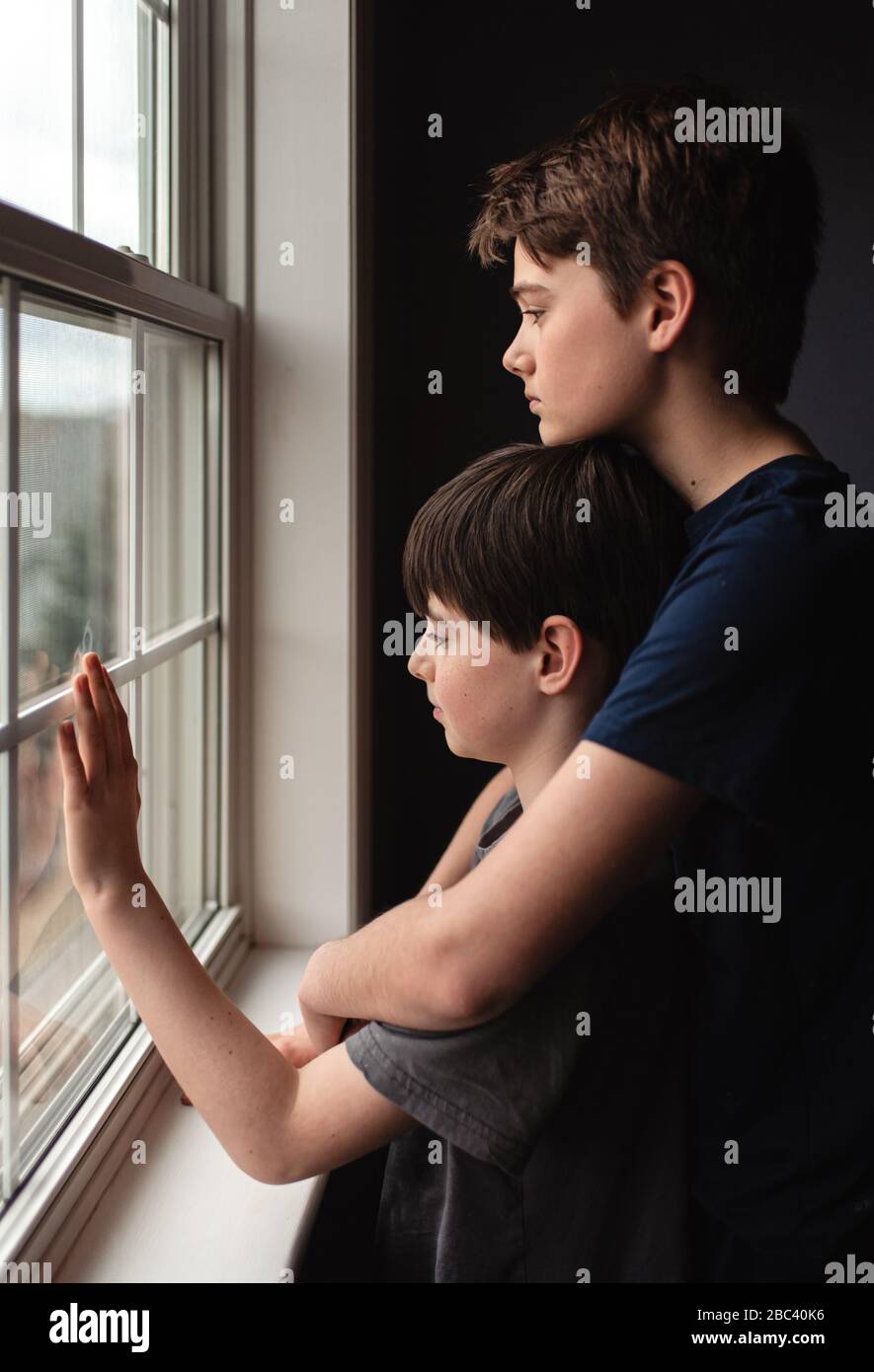Two boys looking out of a window together with sad faces Stock Photo ...