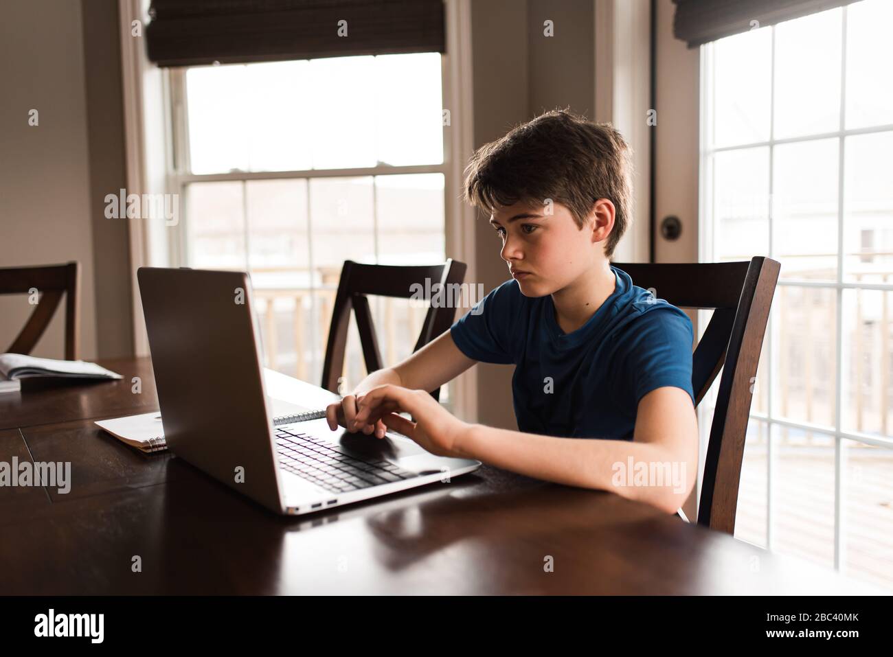 Tween boy working on his homework on a laptop commuter at home Stock ...