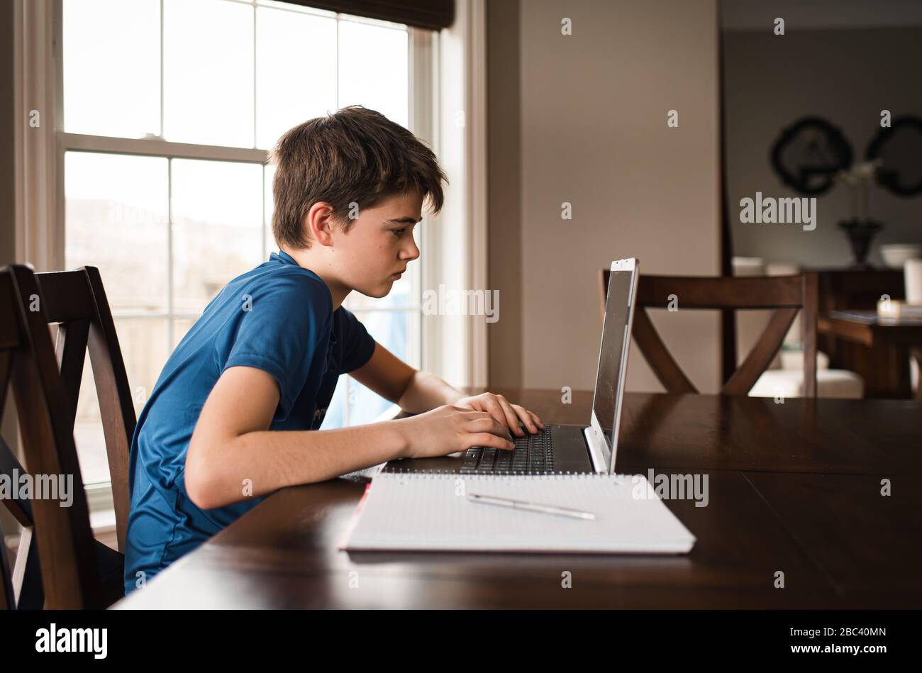 Tween boy working on his homework on a laptop commuter at home Stock ...