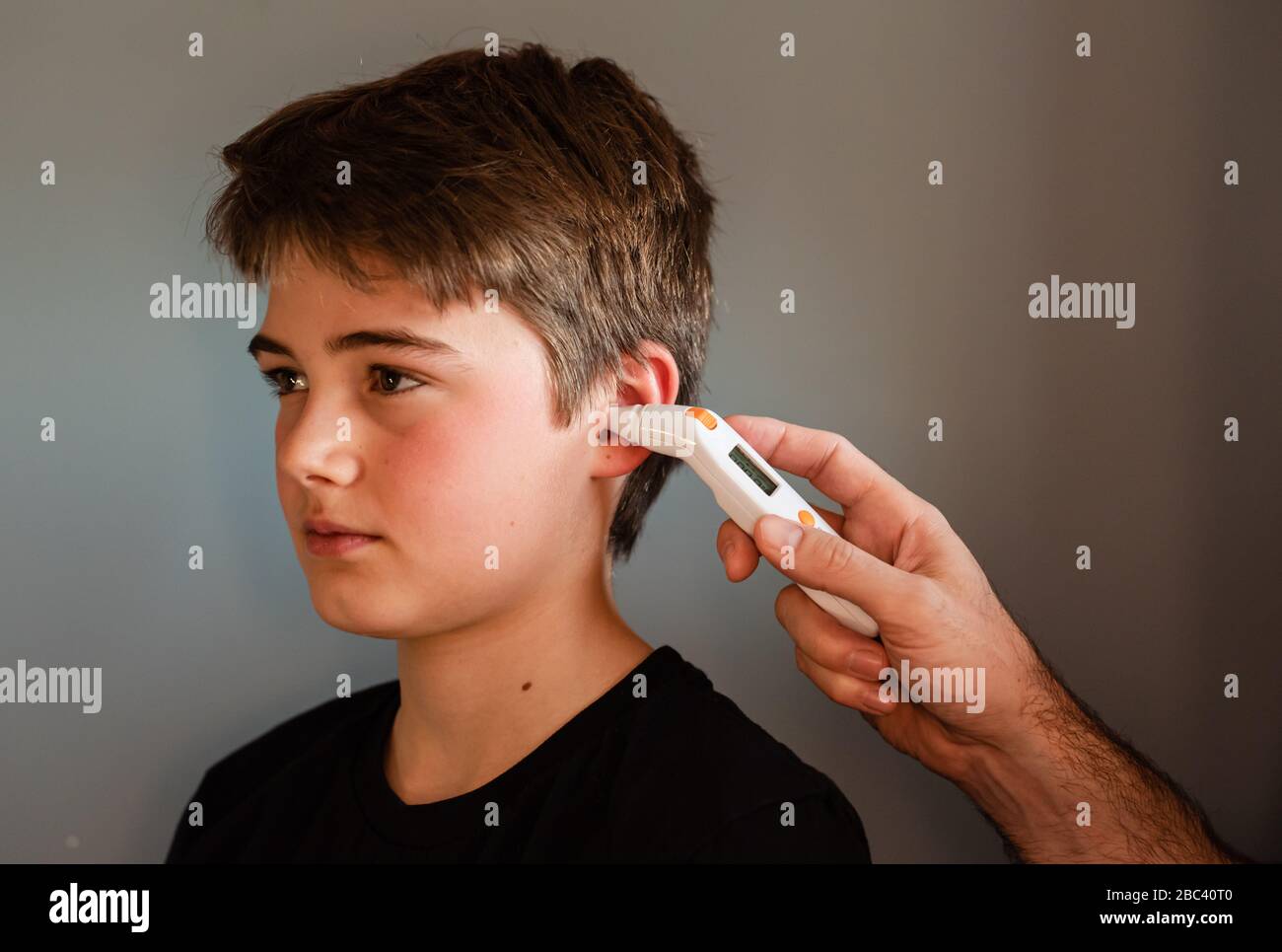 Tween boy getting temperature taken with an ear thermometer Stock Photo ...