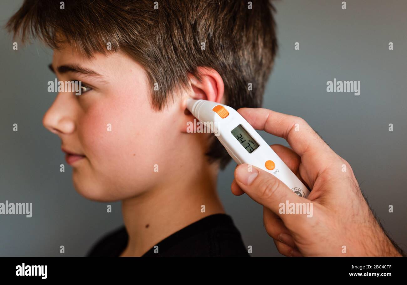 Tween boy getting temperature taken with an ear thermometer Stock Photo ...