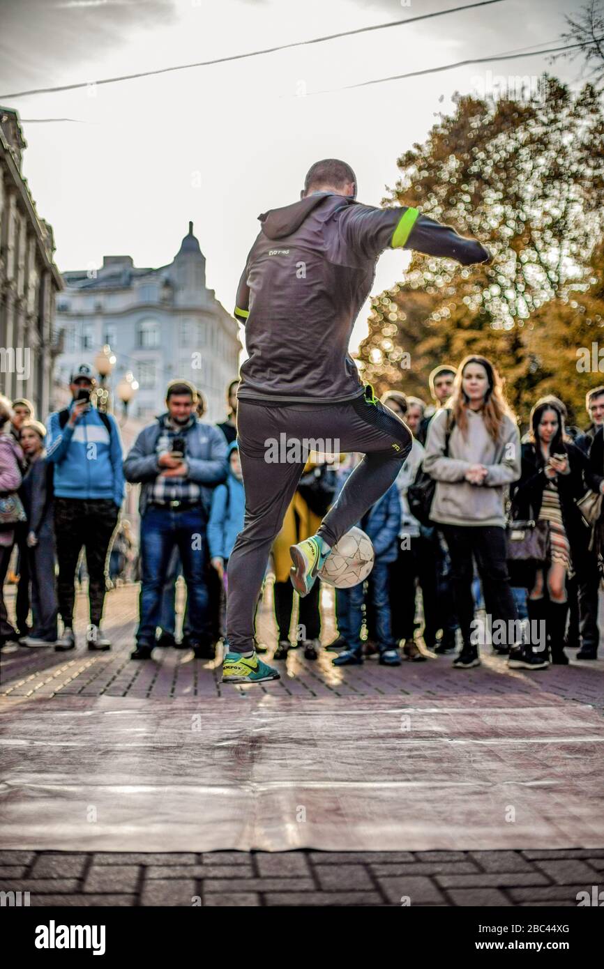 Male street football player professional kicking a ball in mid-air ...