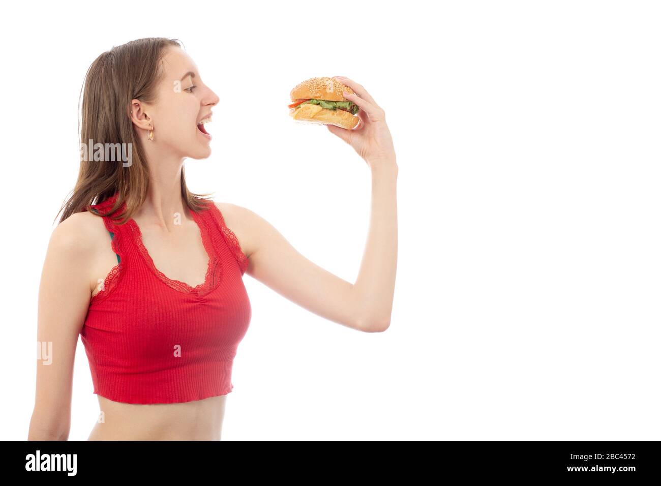 happy young woman eats cheeseburger on white background with copy space ...