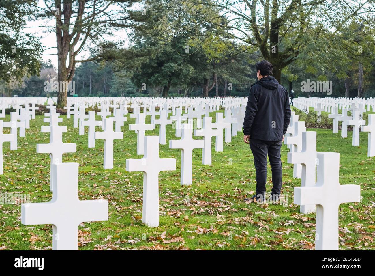 Man standing alone on a graveyard full of crosses. Blank cross Stock ...