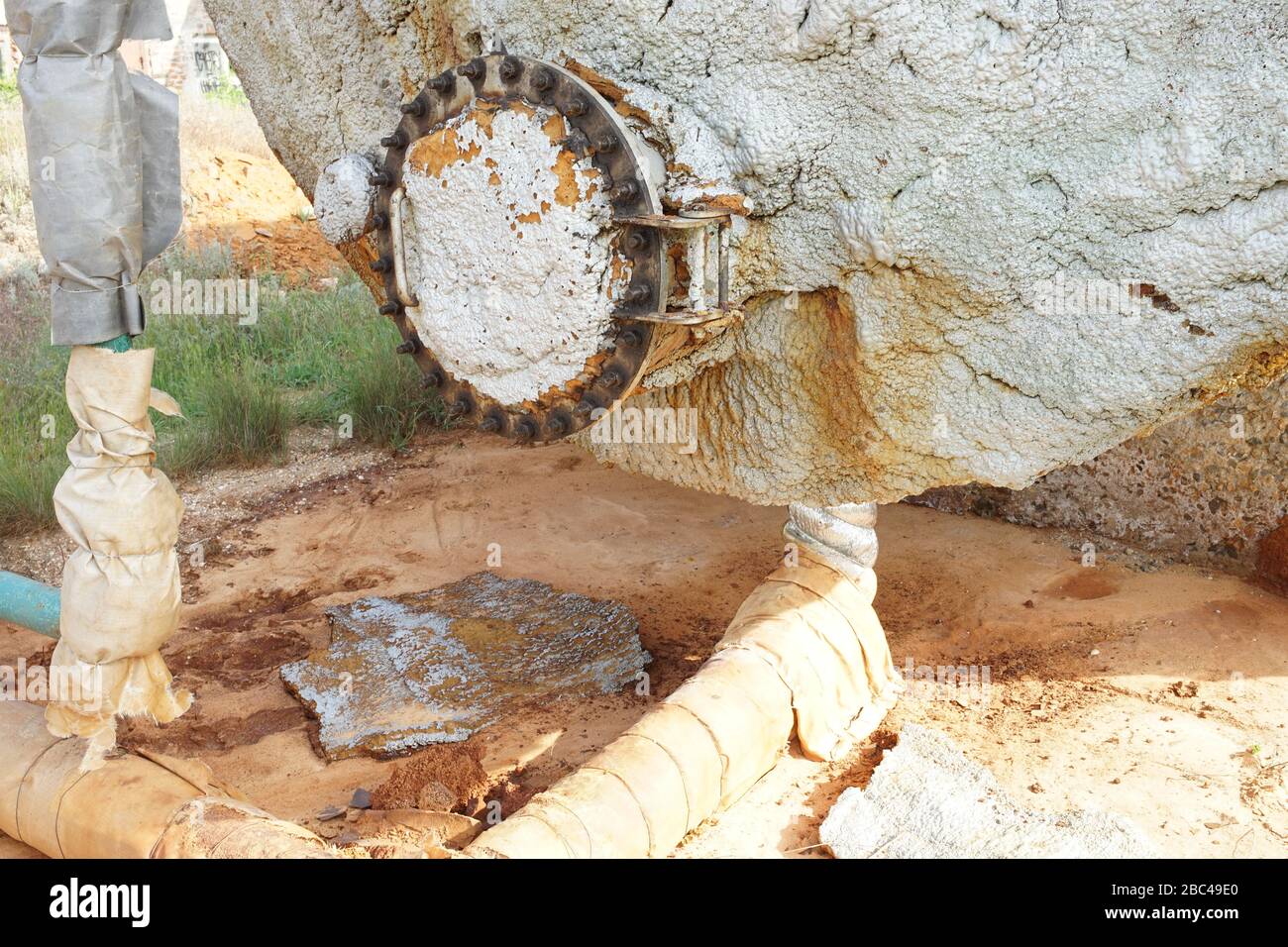 Part of an old rusty tank with a round hatch outdoors, closeup, side ...