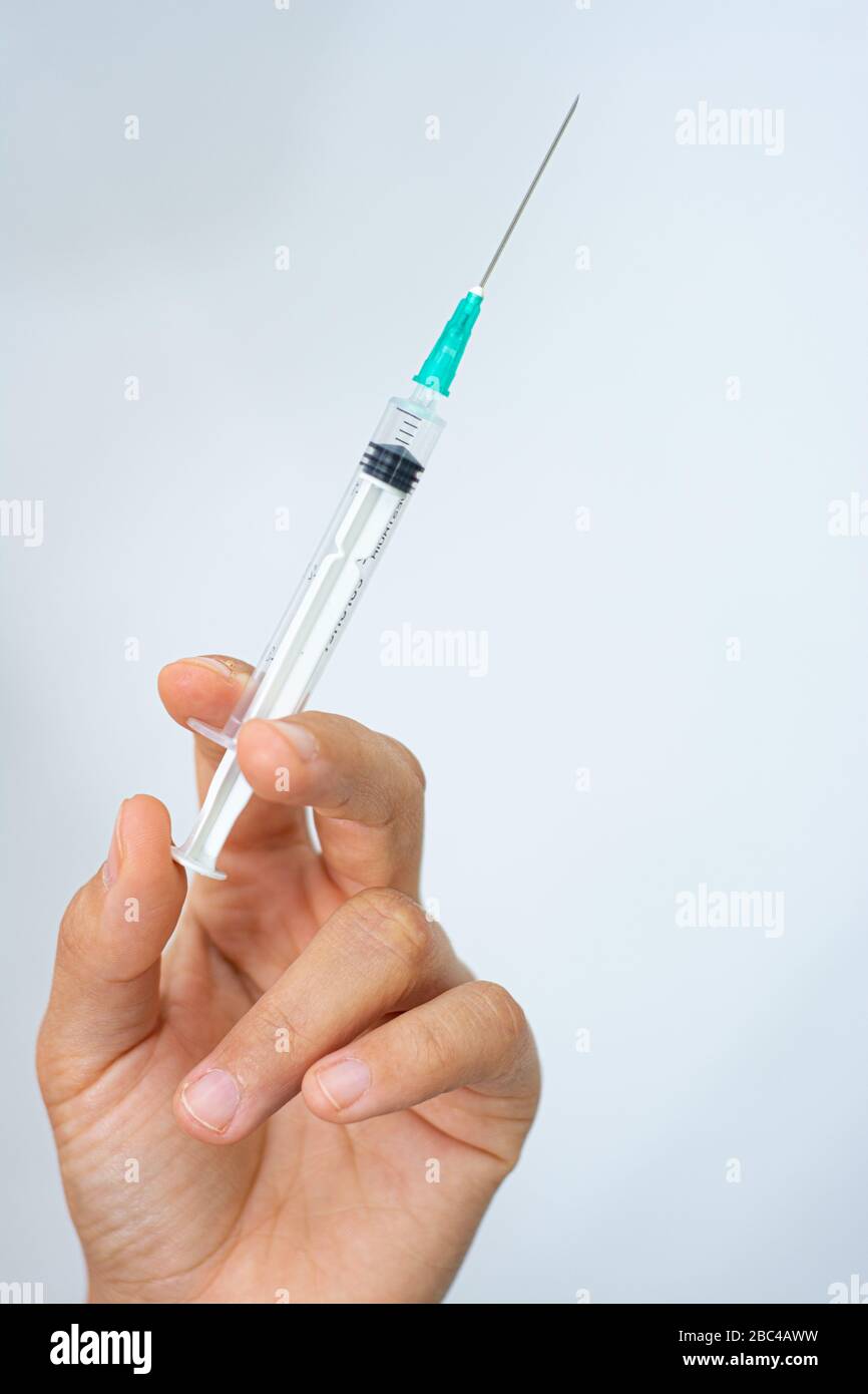 Syringe held by a hand with white background Stock Photo - Alamy