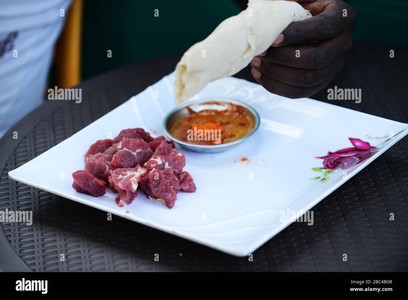 An Ethiopian man eating Injera be tire siga ( injera with raw meat ...