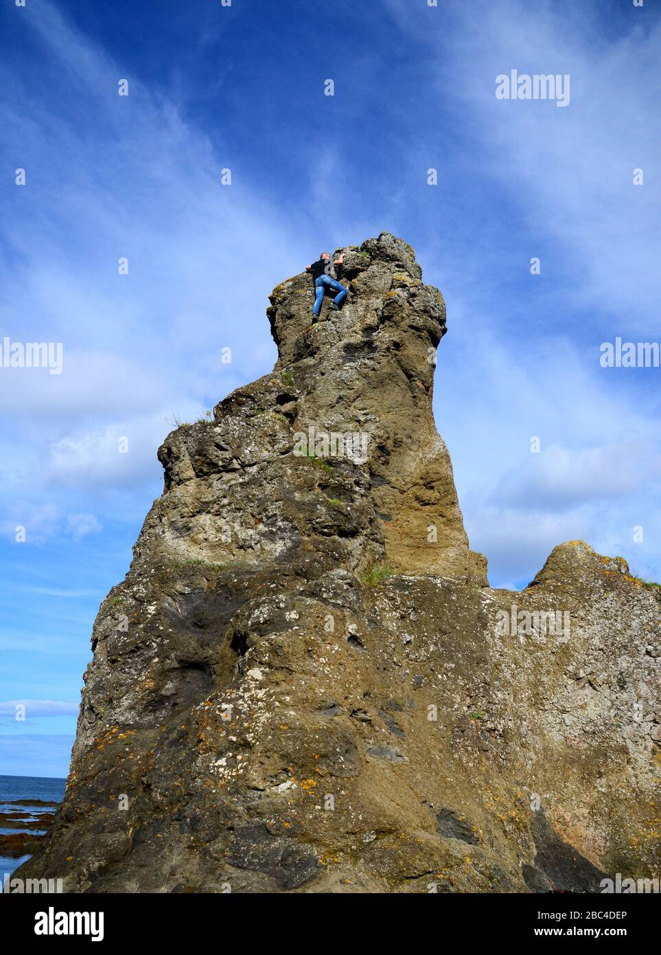 A young man / teenager free climbing up a rocky cliff face Stock Photo ...