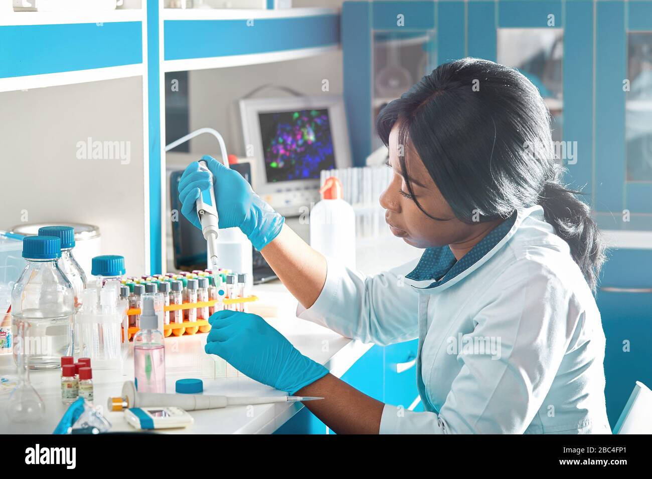 African scientist or graduate student in lab coat and nitril gloves ...