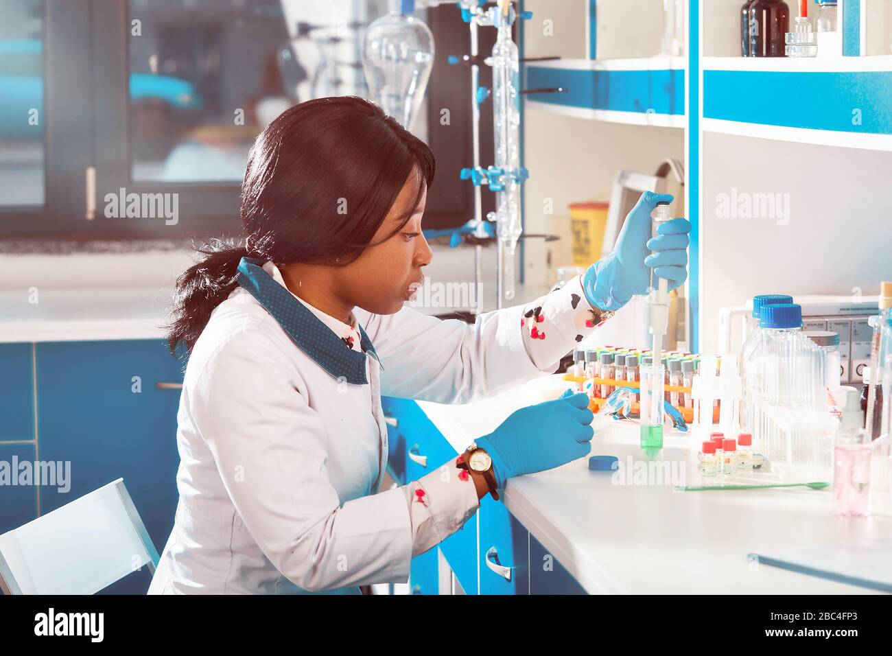 African scientist or graduate student in lab coat and protective wear ...