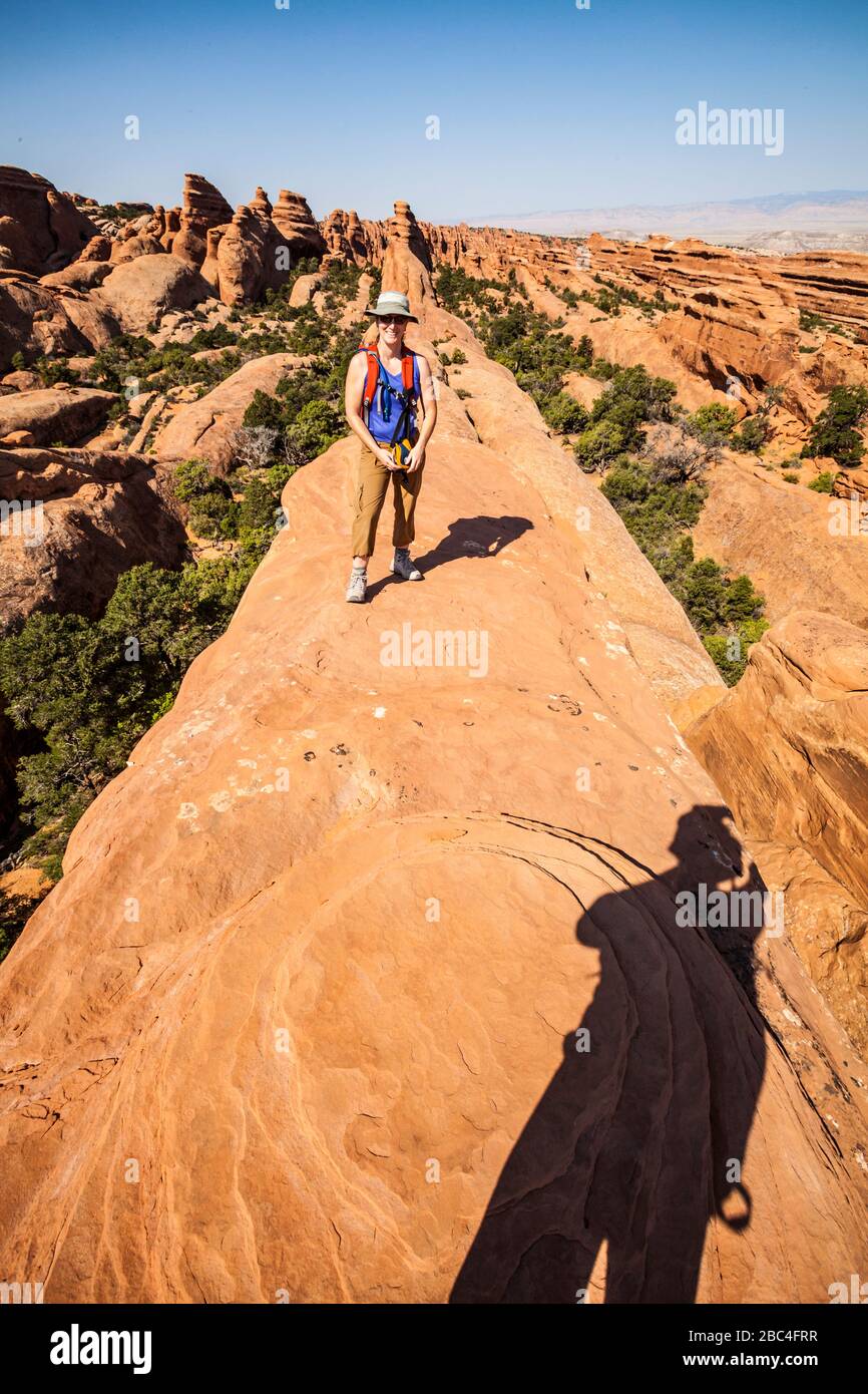 A woman hiking a sandstone fin in Devils Garden area of Arches National ...