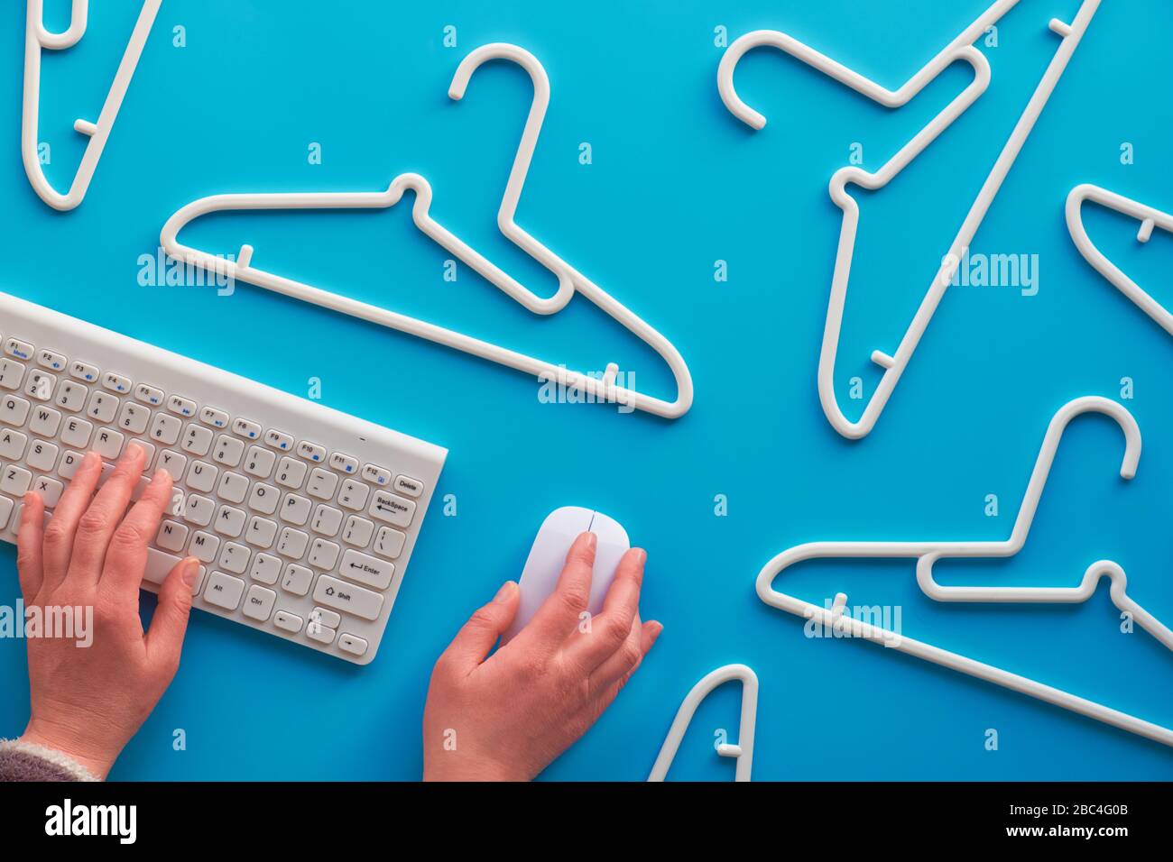 White plastic hangers, hands with keyboard and computer mouse. Creative ...