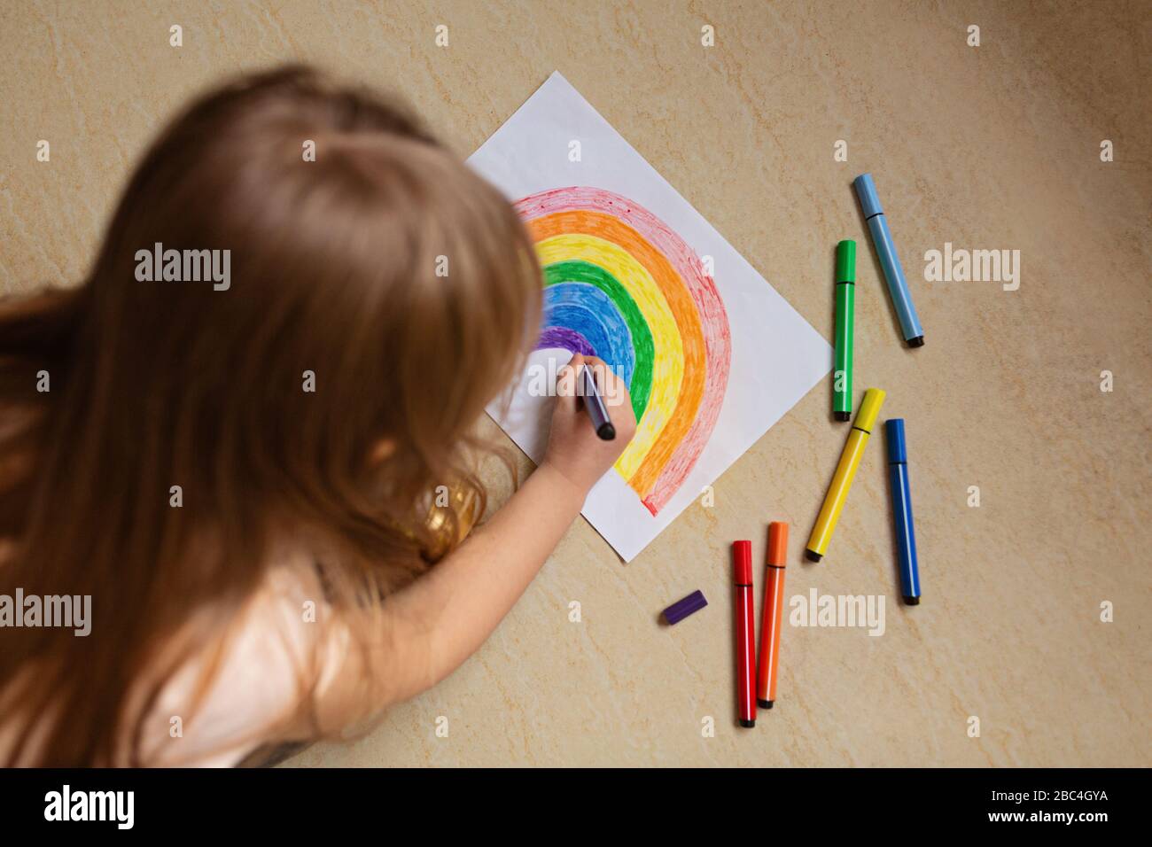 Kid painting rainbow during Covid-19 quarantine at home. Stay at home ...