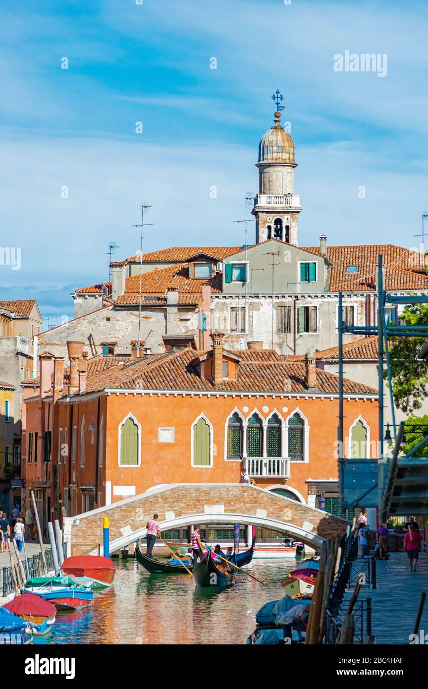 Gondoliers passing under small bridge on a venetian canal Stock Photo ...