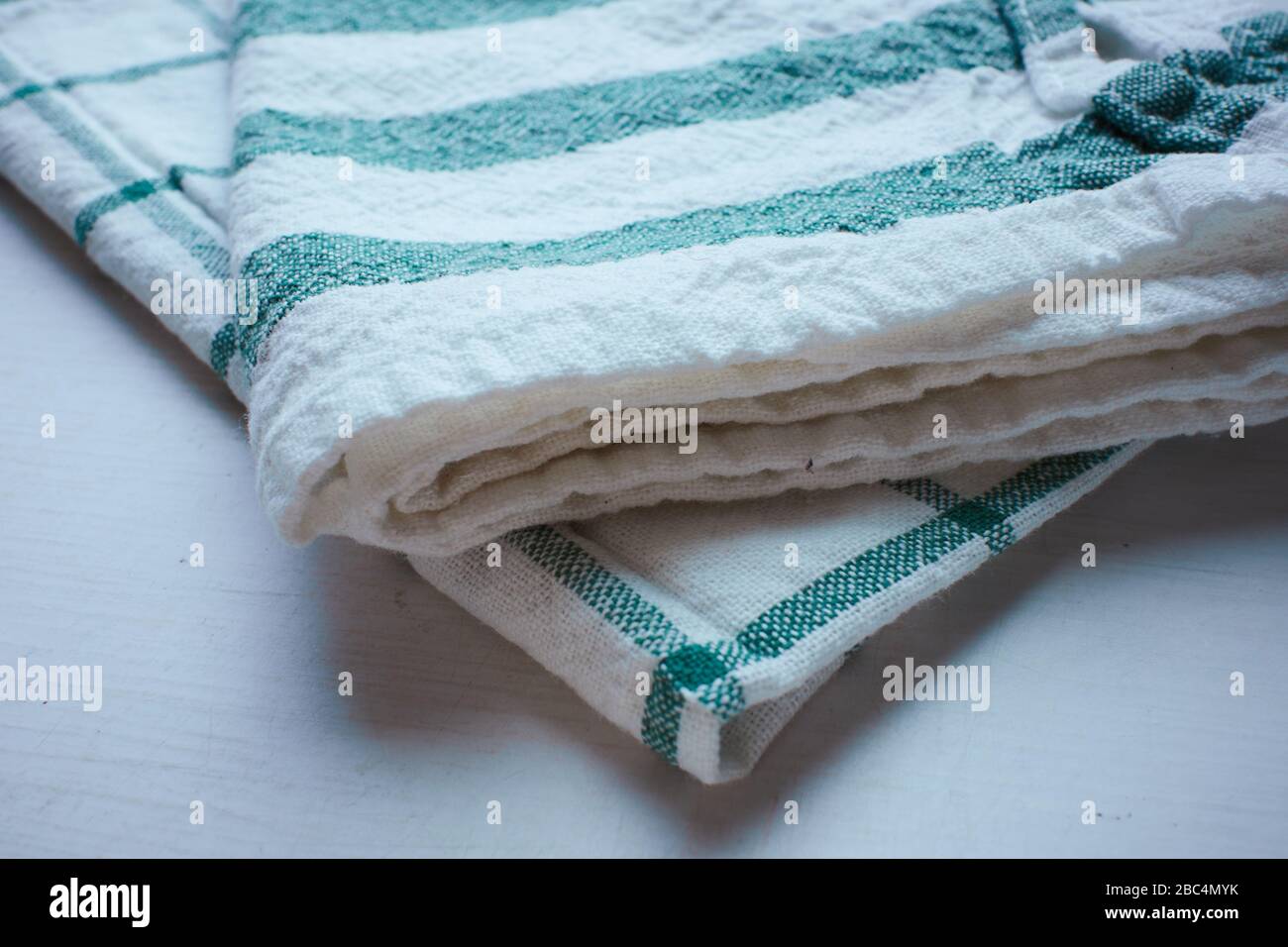 two green and white striped cotton tea towels on a white-ish background ...