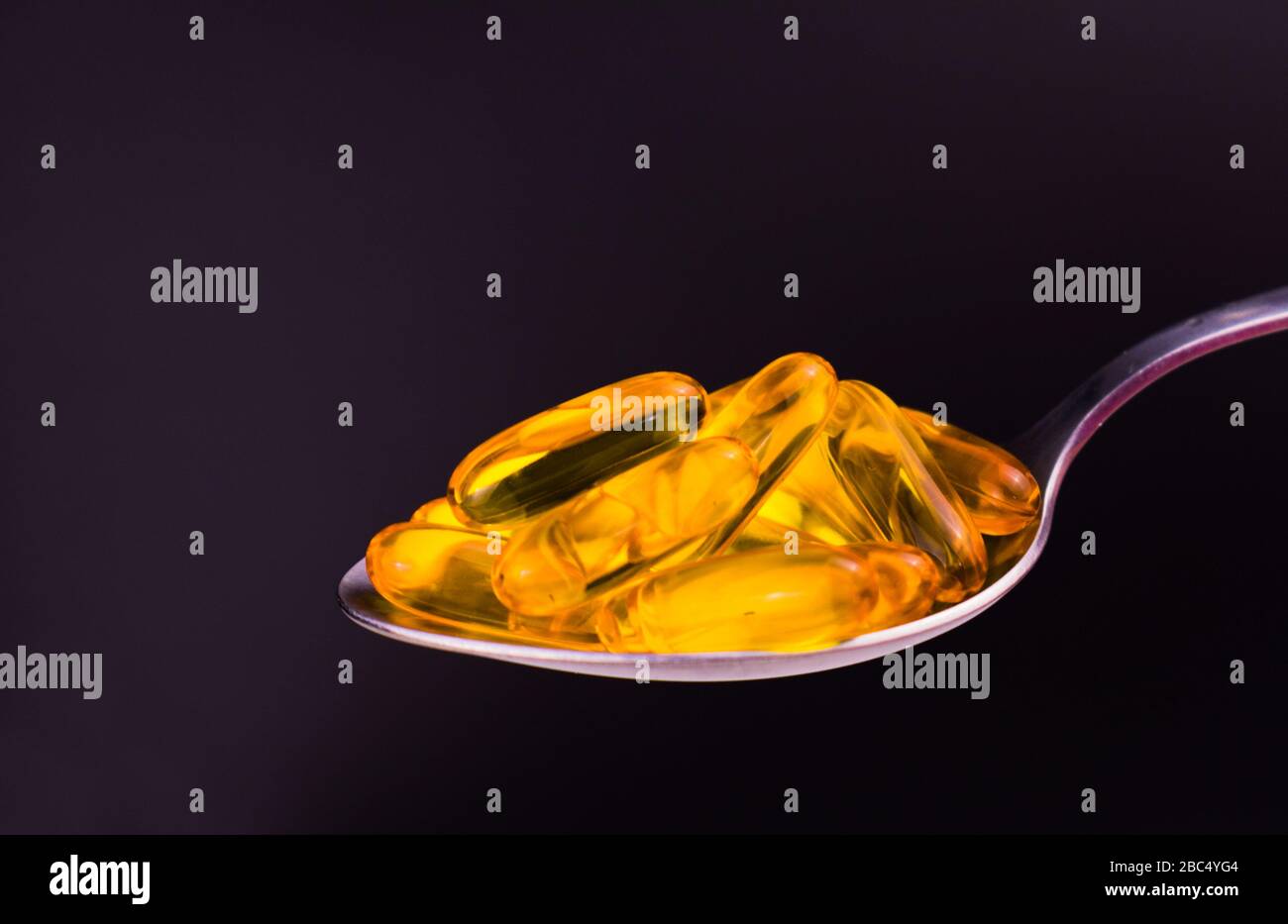Useful omega 3 capsules in a spoon on a black background. Copy space ...