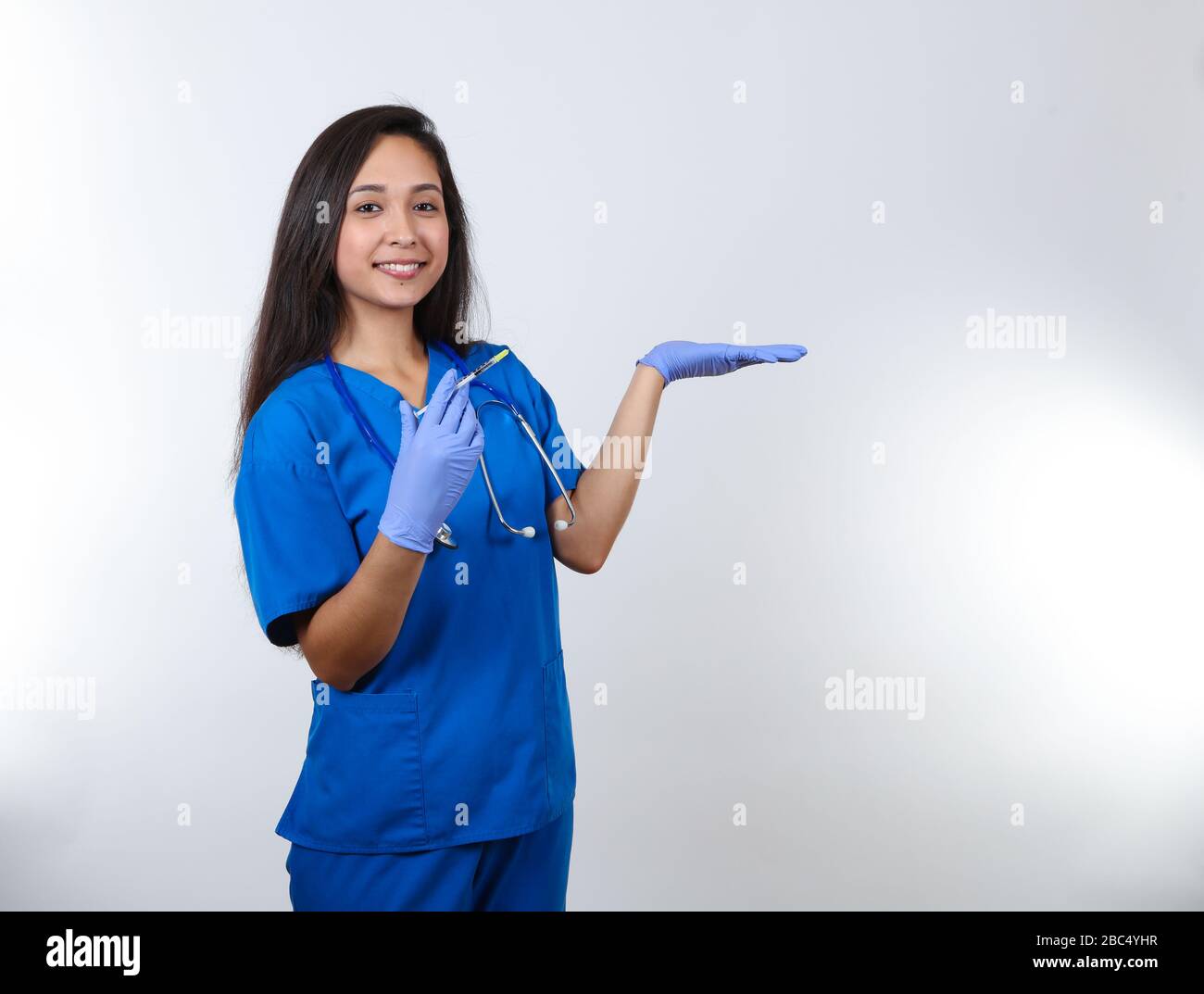 An energetic nurse in scrubs holds a syringe and her hand up Stock ...