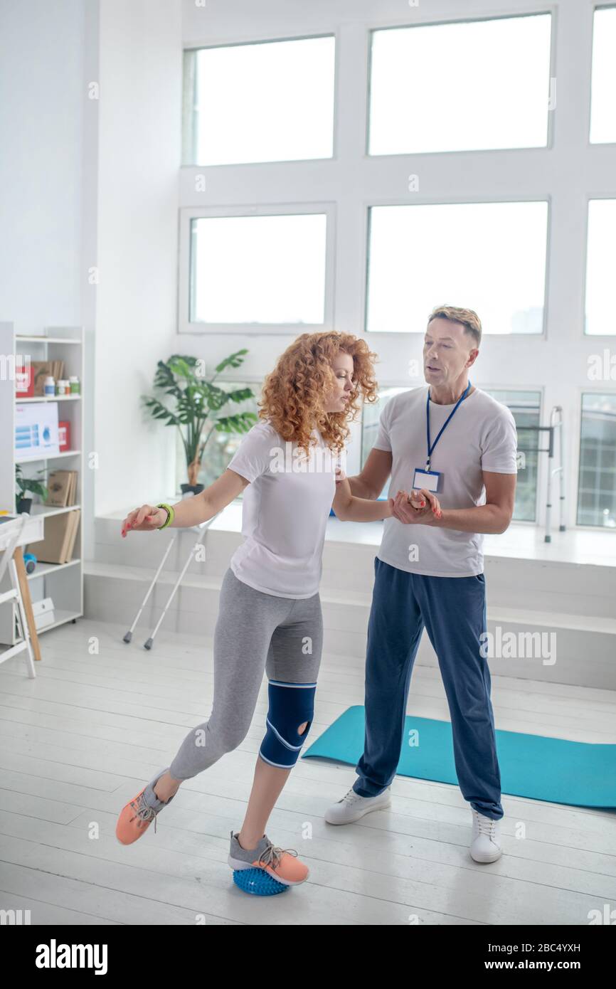 Male physiotherapist helping female patient keep balance Stock Photo ...