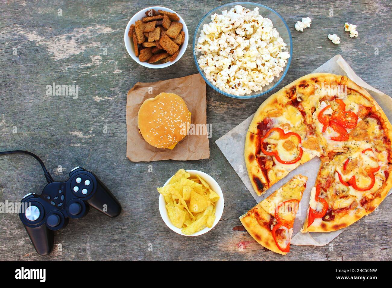 Fast food and video game controller on old wooden background. Concept ...