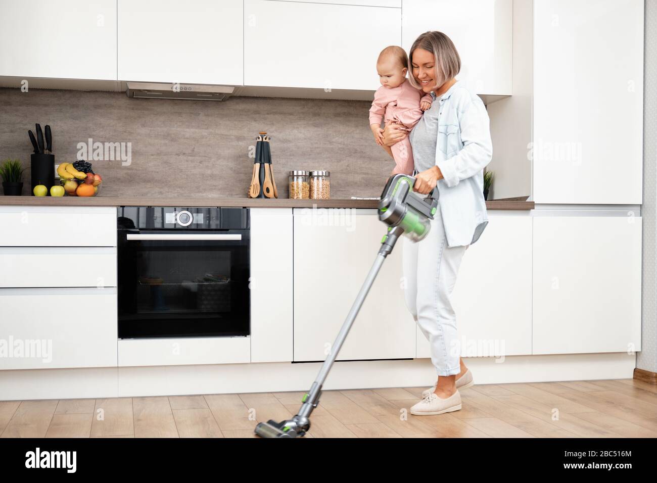 Vacuuming and Cleaning the House. Happy mother with her Baby in her ...