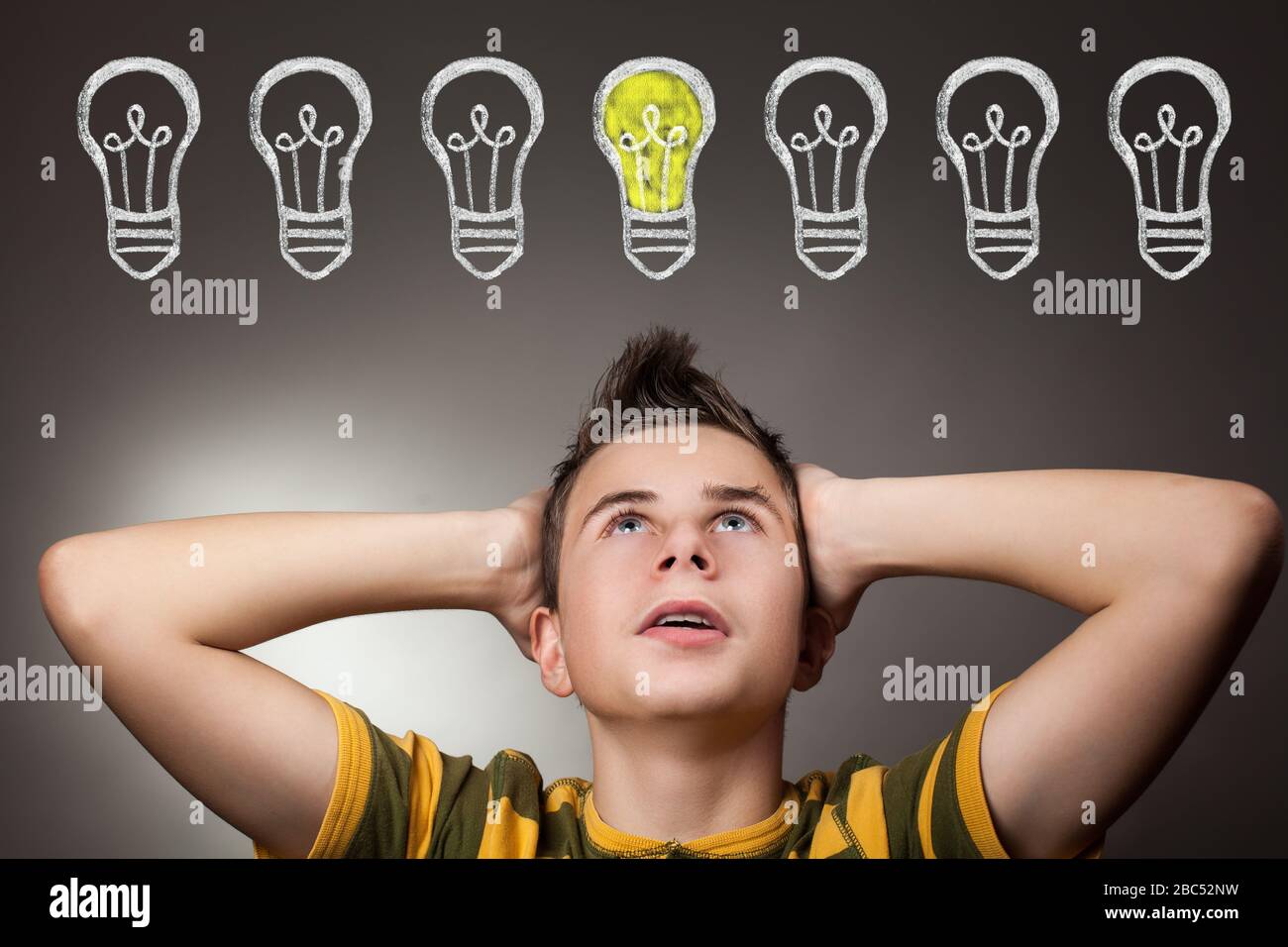 Young boy looking up at light idea bulb above head Stock Photo - Alamy