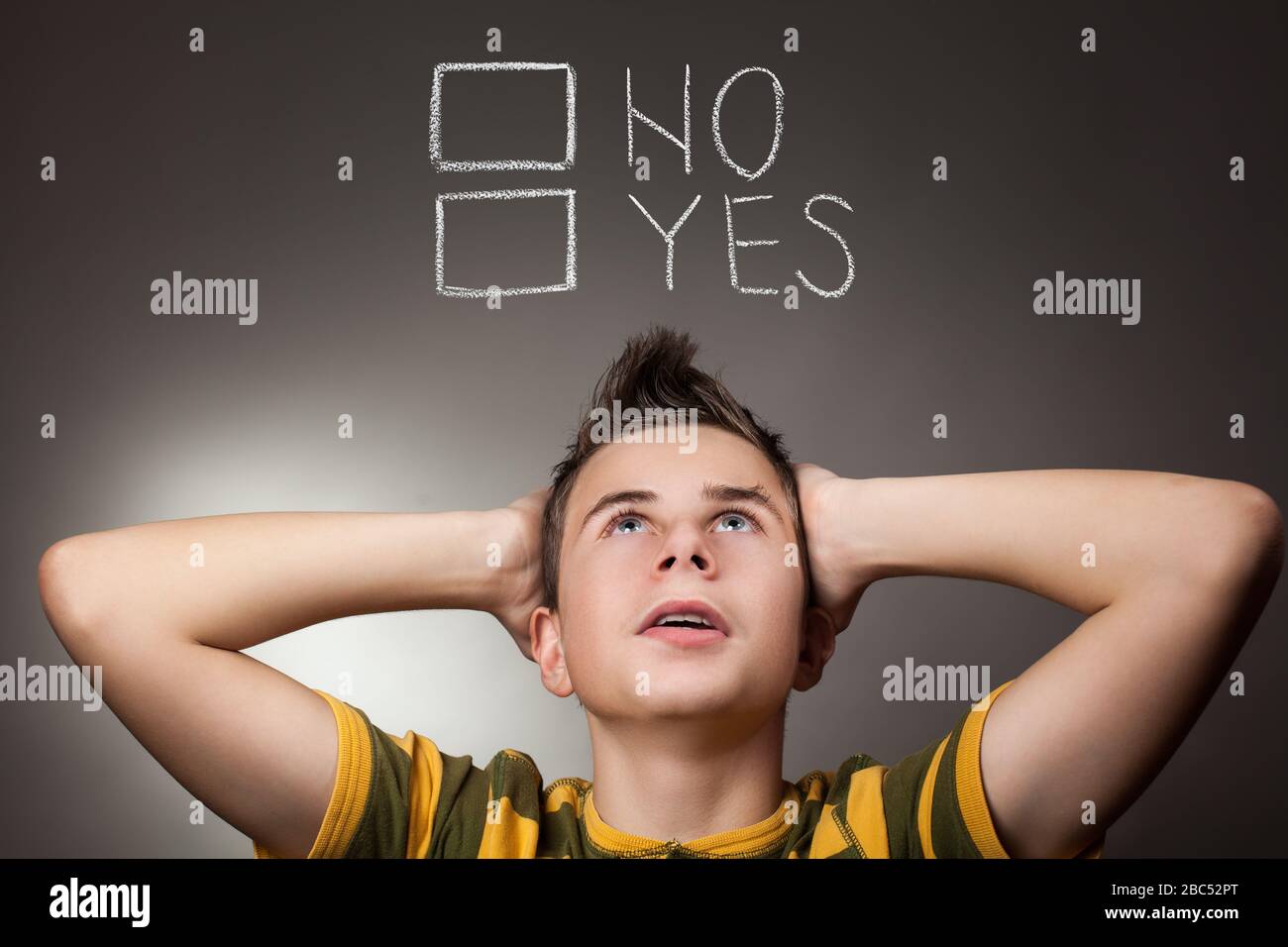 Young boy looking up at Yes and No words Stock Photo - Alamy