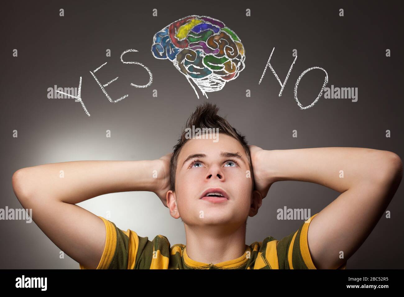 Young boy looking up at Yes and No words Stock Photo - Alamy