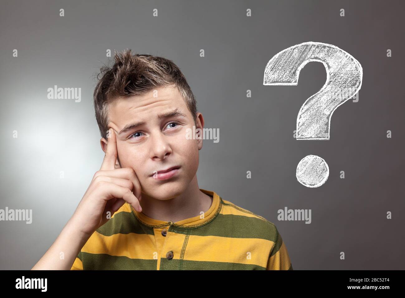 Young boy looking up at question sign in background Stock Photo - Alamy