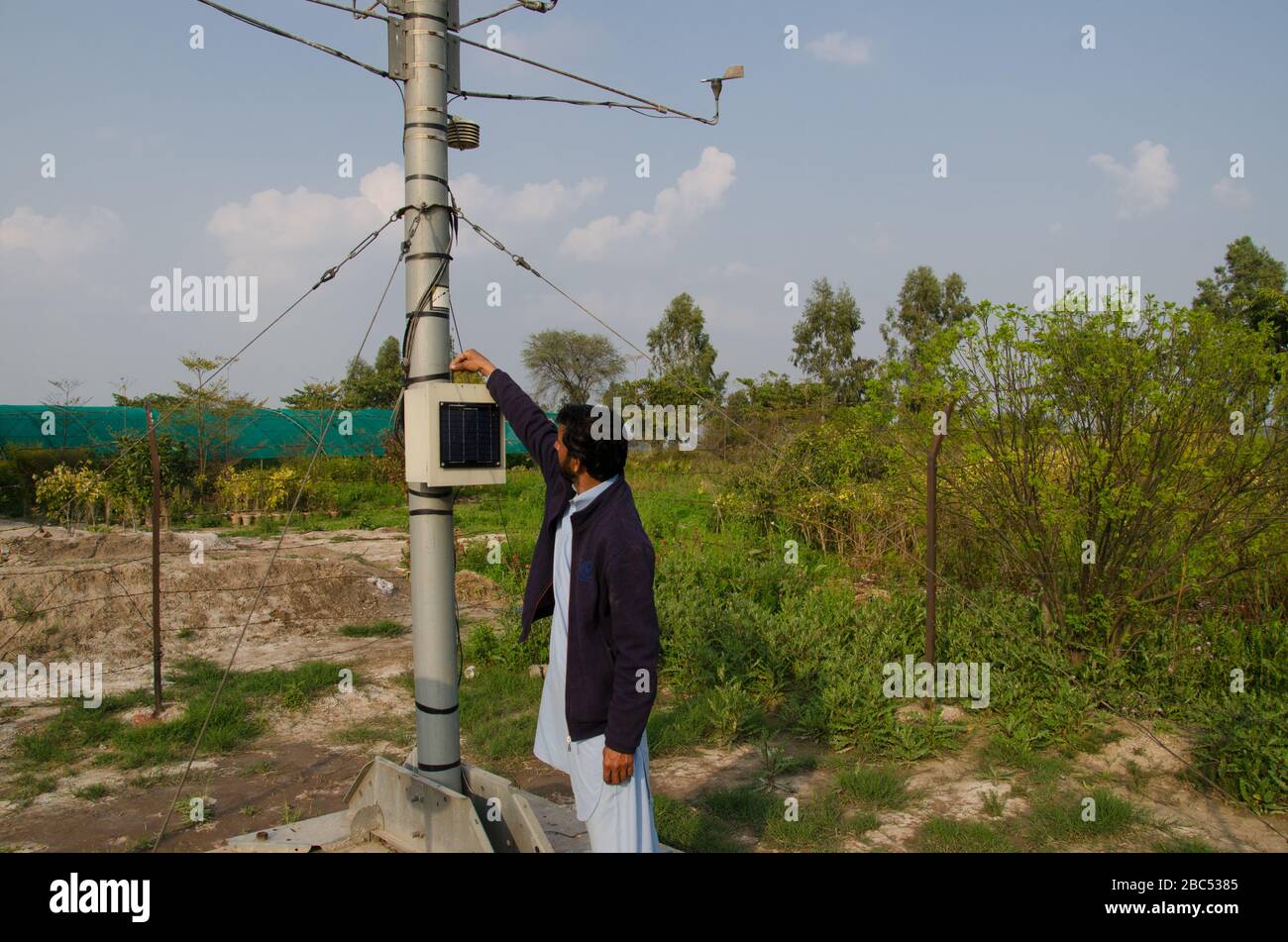 A farm worker checks reading on a weather machine at Kasuri Agri Farm ...