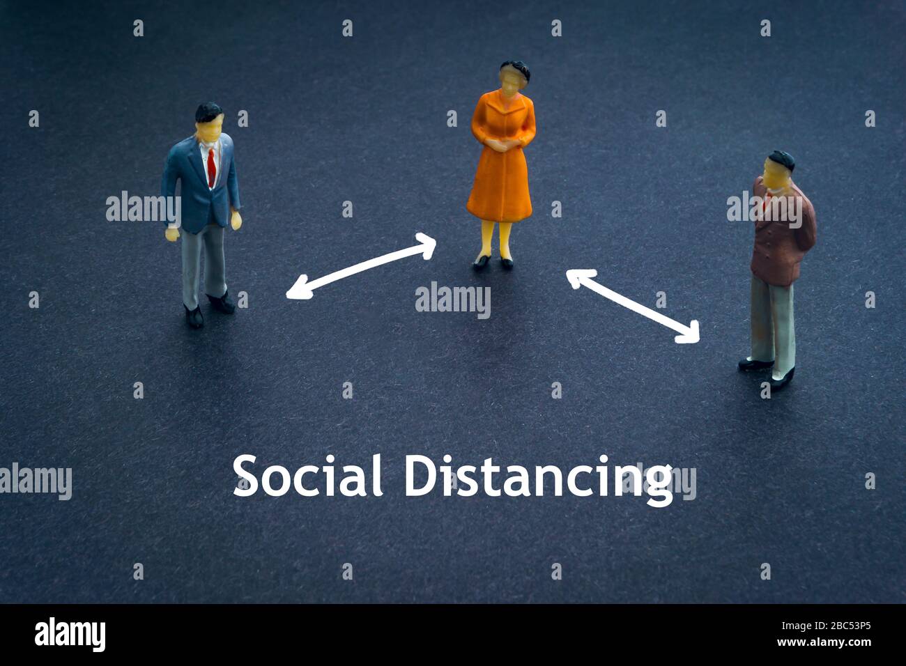 SOCIAL DISTANCING text with miniature people on dark background. Covid ...