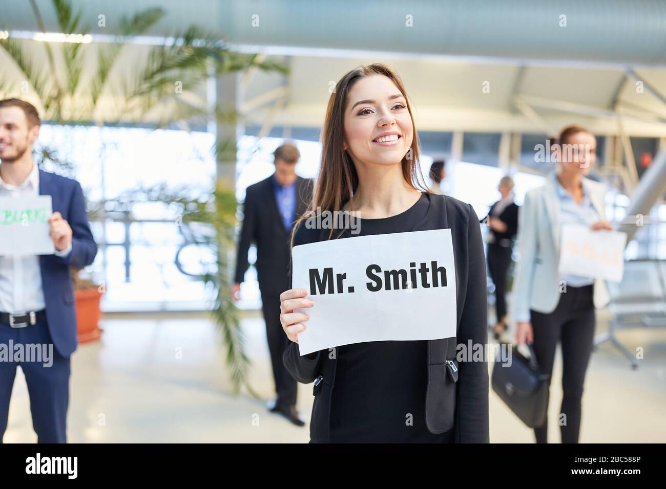 Businesswoman with name tag at airport picking up from a guest Stock ...