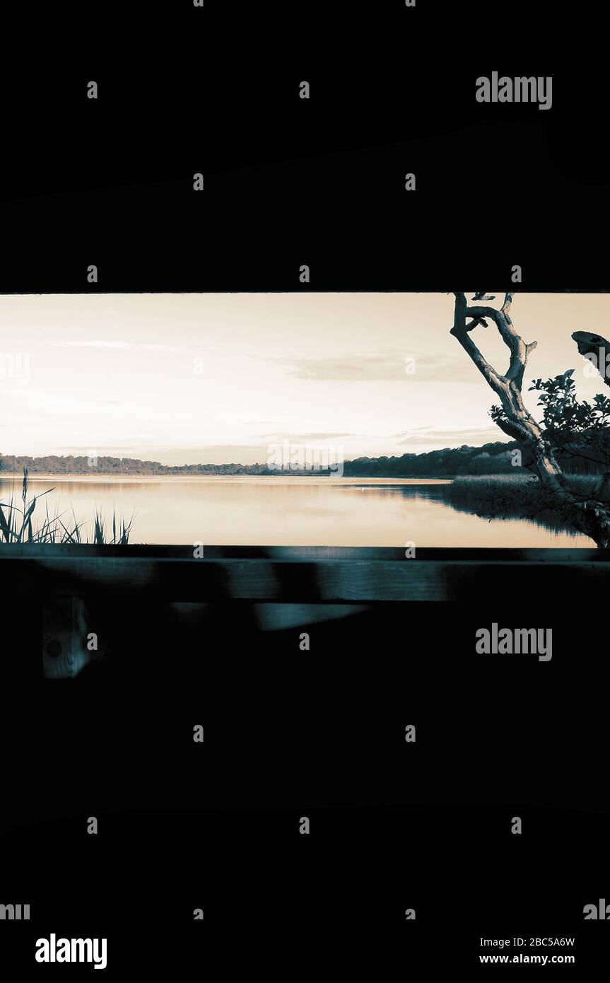 View of a nature reserve lake through a bird hide window. With colour ...