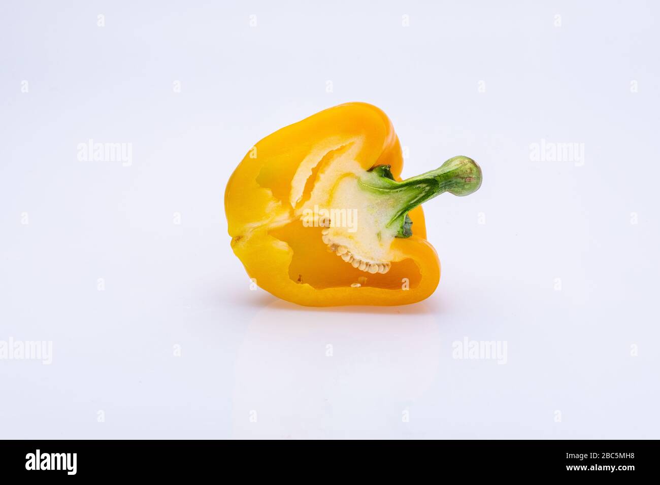 Yellow pepper sliced in half isolated in front of a white background ...
